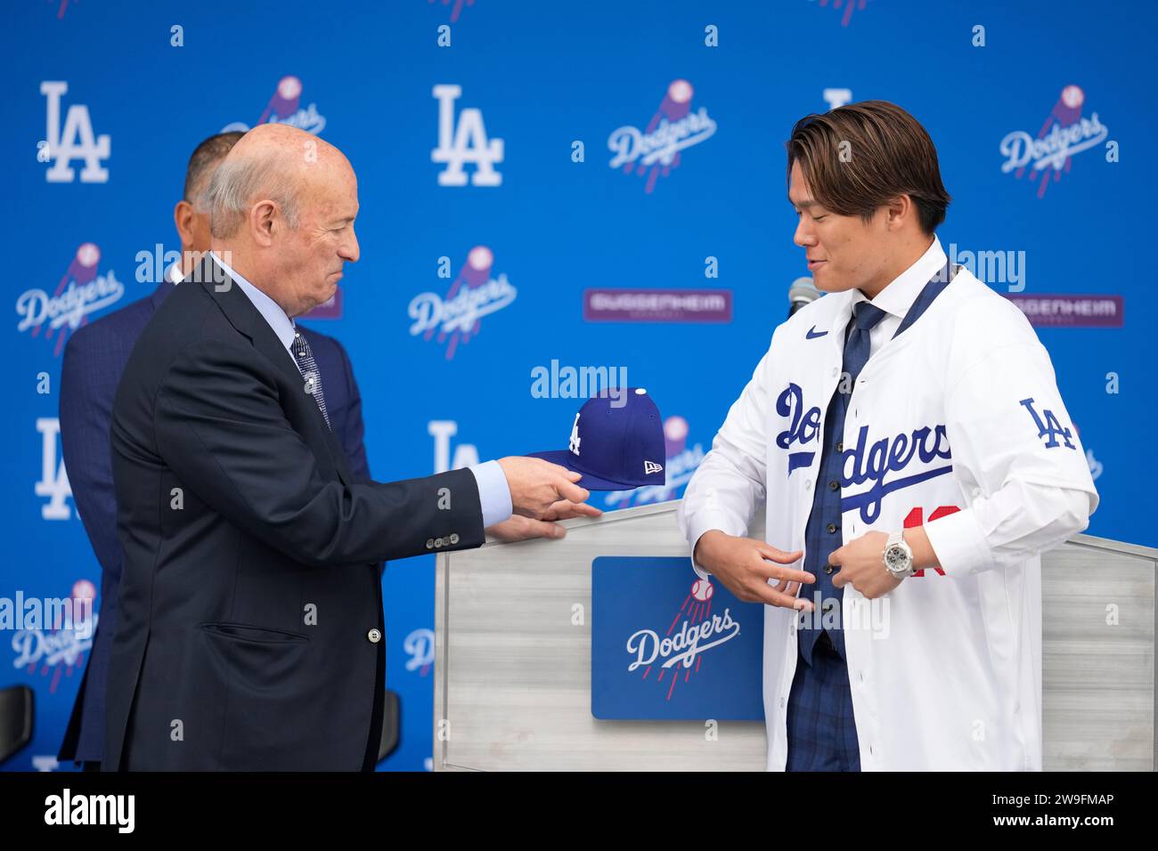 Yoshinobu Yamamoto, left, puts on a Dodgers jersey next to president ...
