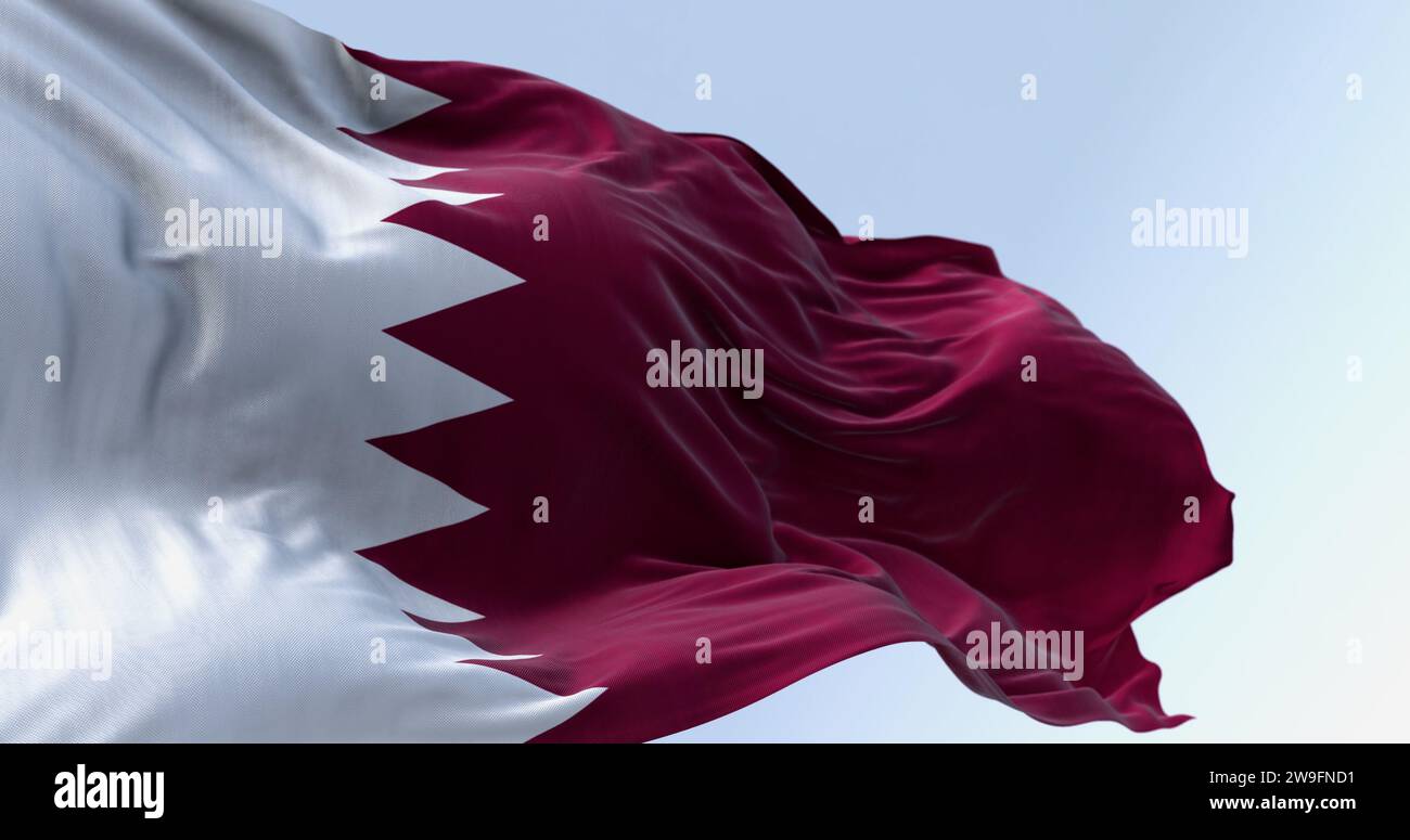 Detail of the Qatar national flag fluttering. The flag is maroon with a ...