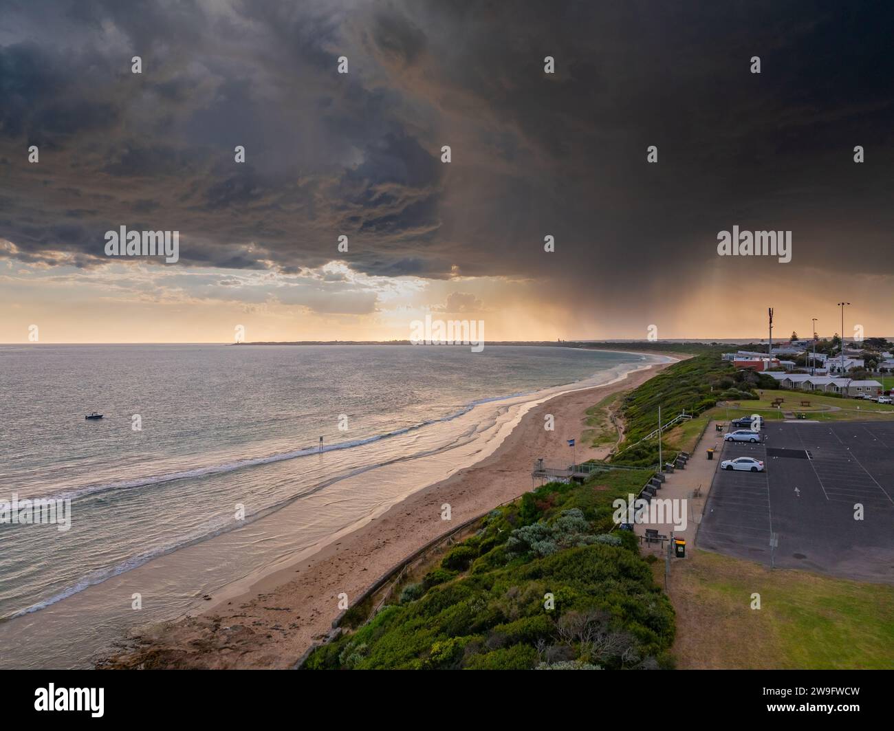 Aerial view of a rain storm in front of a coastal sunset 0ver a carpark ...