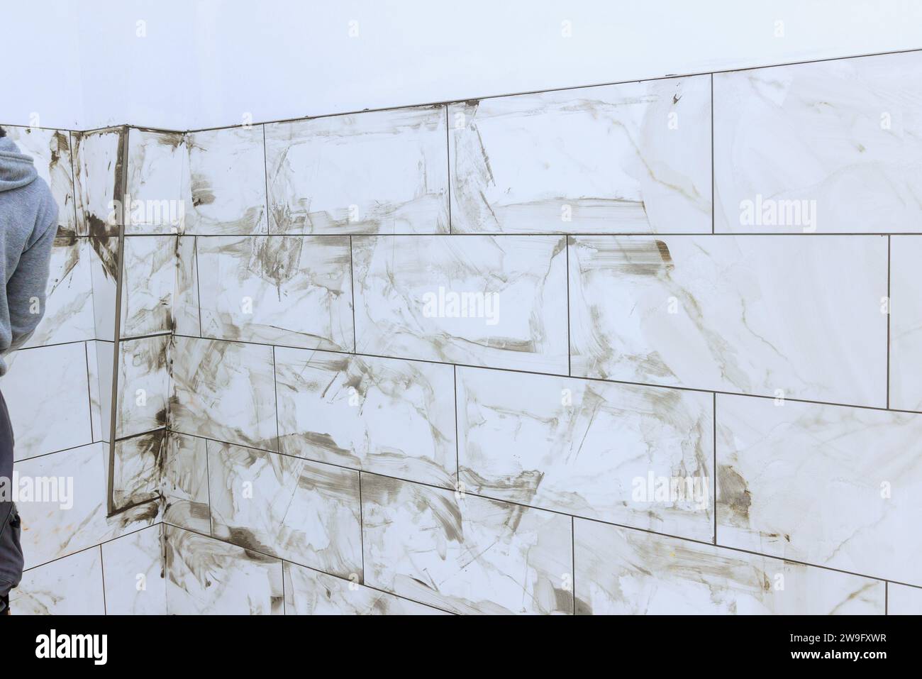 Ceramic tiles are grouted with rubber trowel by tilers filling gap ...