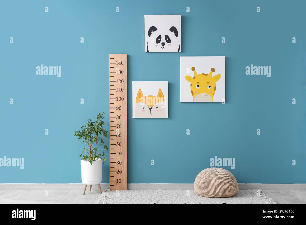 Wooden stadiometer with cute animal paintings and houseplant near blue ...