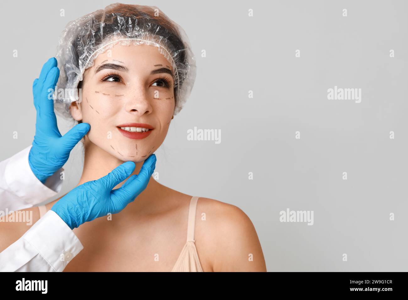 Young woman with marked face and plastic surgeon on light background ...