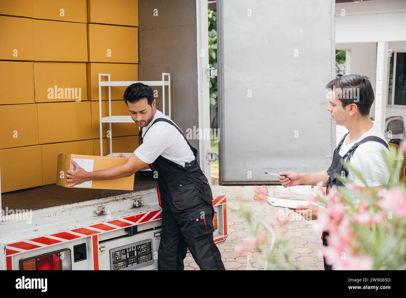 Two movers from a relocation company unload boxes exhibiting teamwork ...