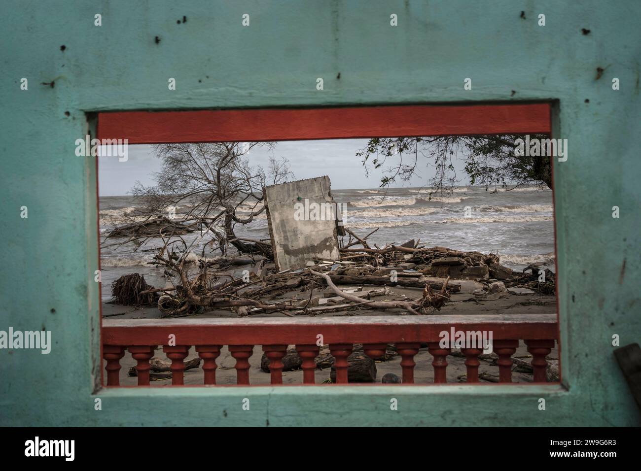 A window frames a portion of a shoreline littered with debris from ...