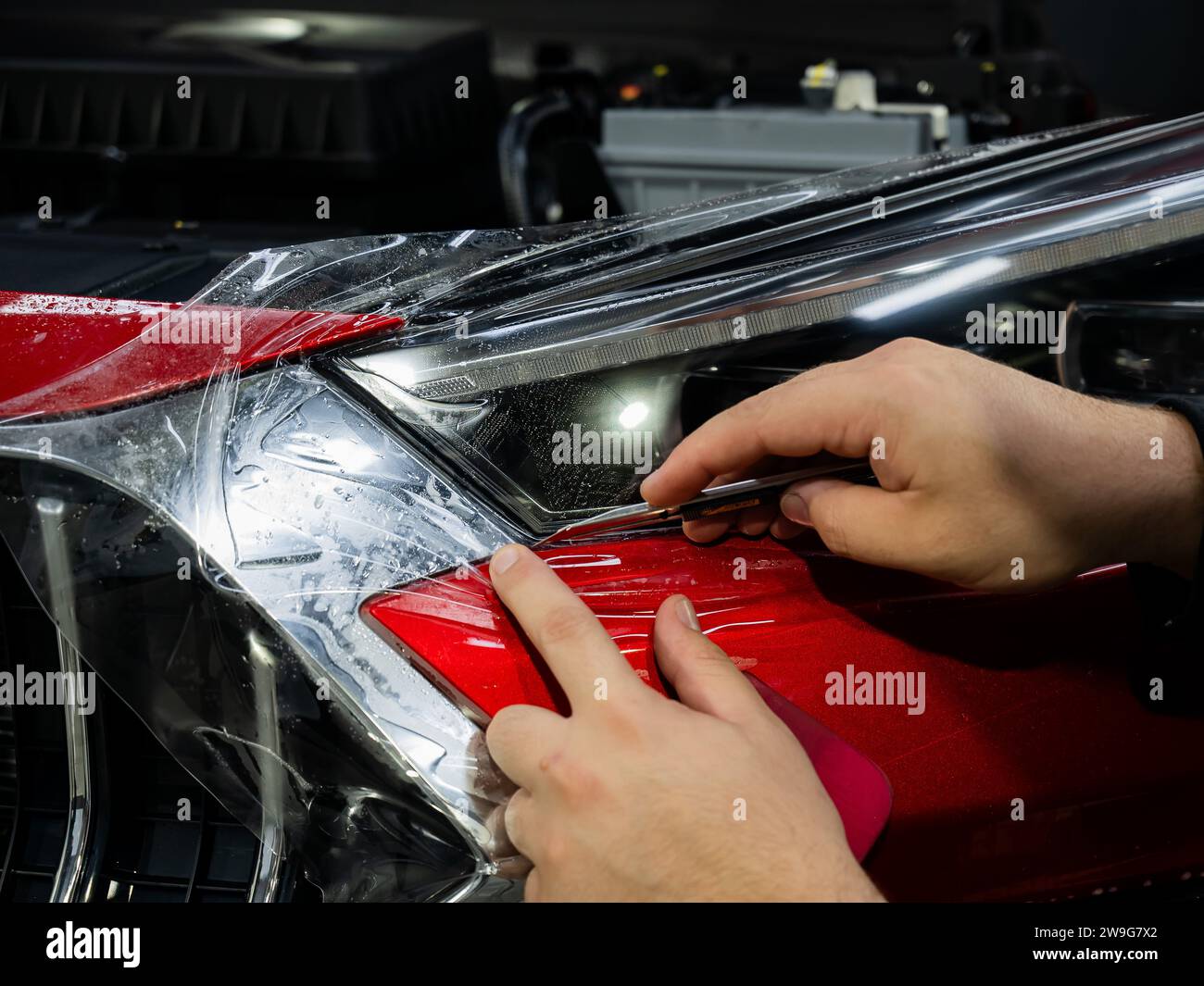 The process of applying protective vinyl film to car headlights in ...
