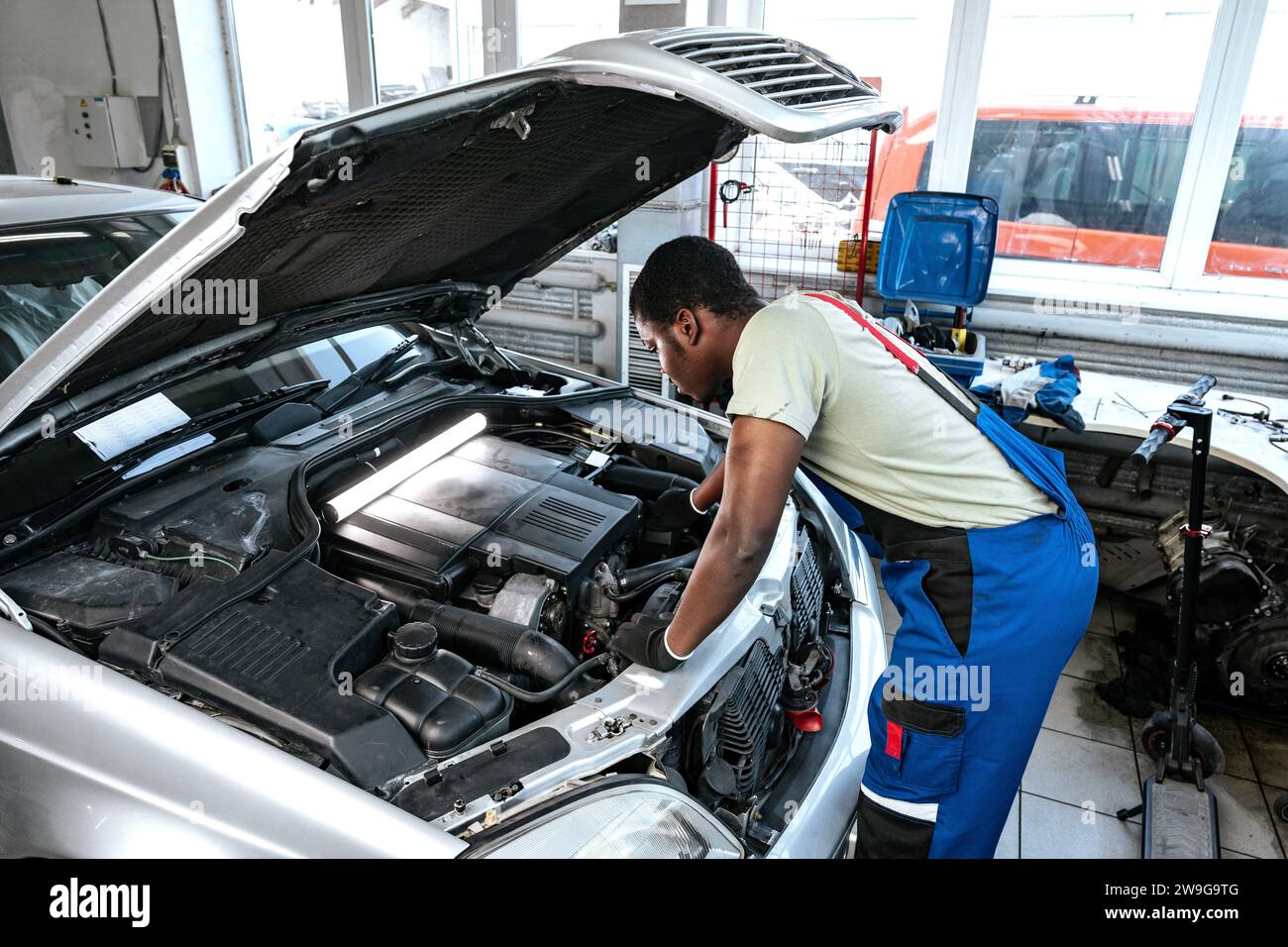 Young African man working under the hood of car fixing engine in auto service Stock Photo - Alamy