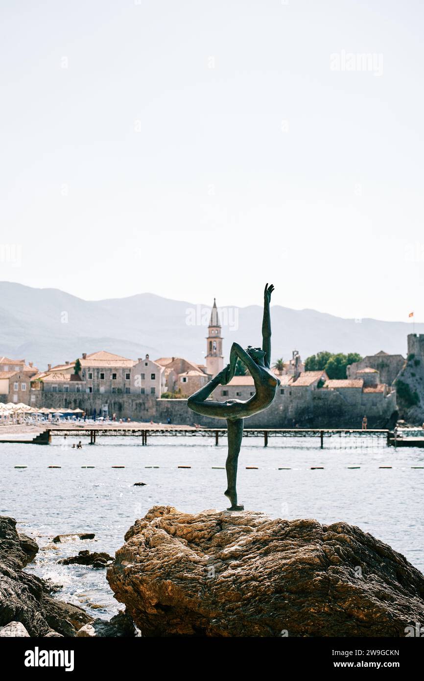 Statue of a dancing ballerina on a stone by the sea against the ...