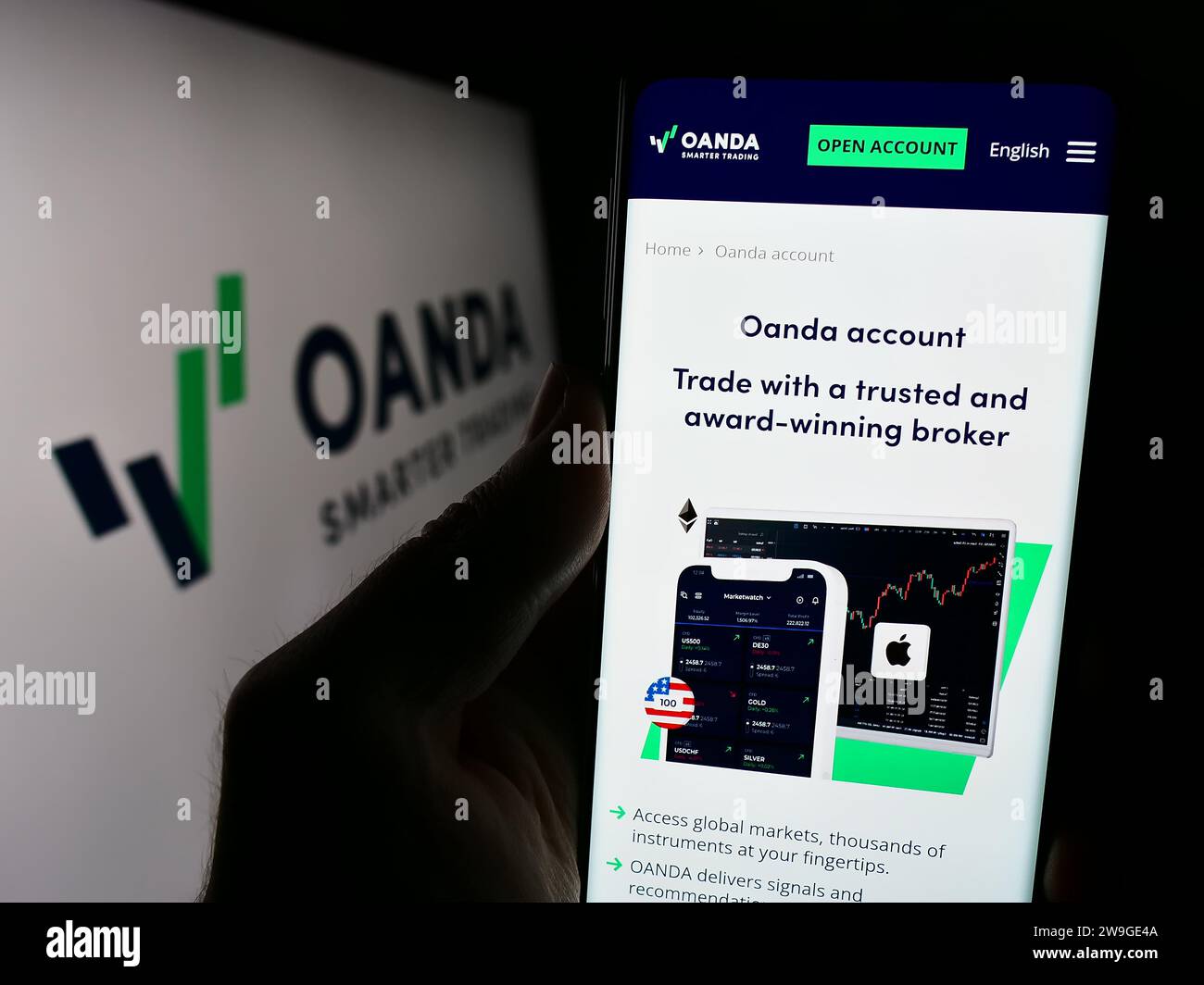 Person holding cellphone with webpage of US company OANDA Business ...