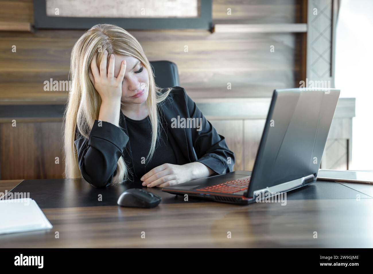 Distressed young business woman in black suit is sitting with eyes ...
