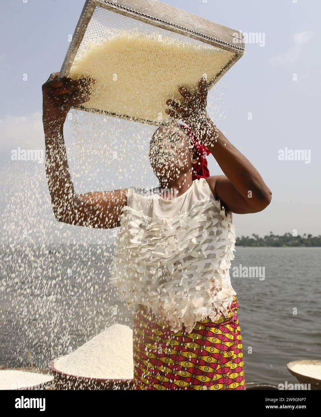Abidjan, Cote d'Ivoire. 27th Dec, 2023. A woman sifts cassava root ...