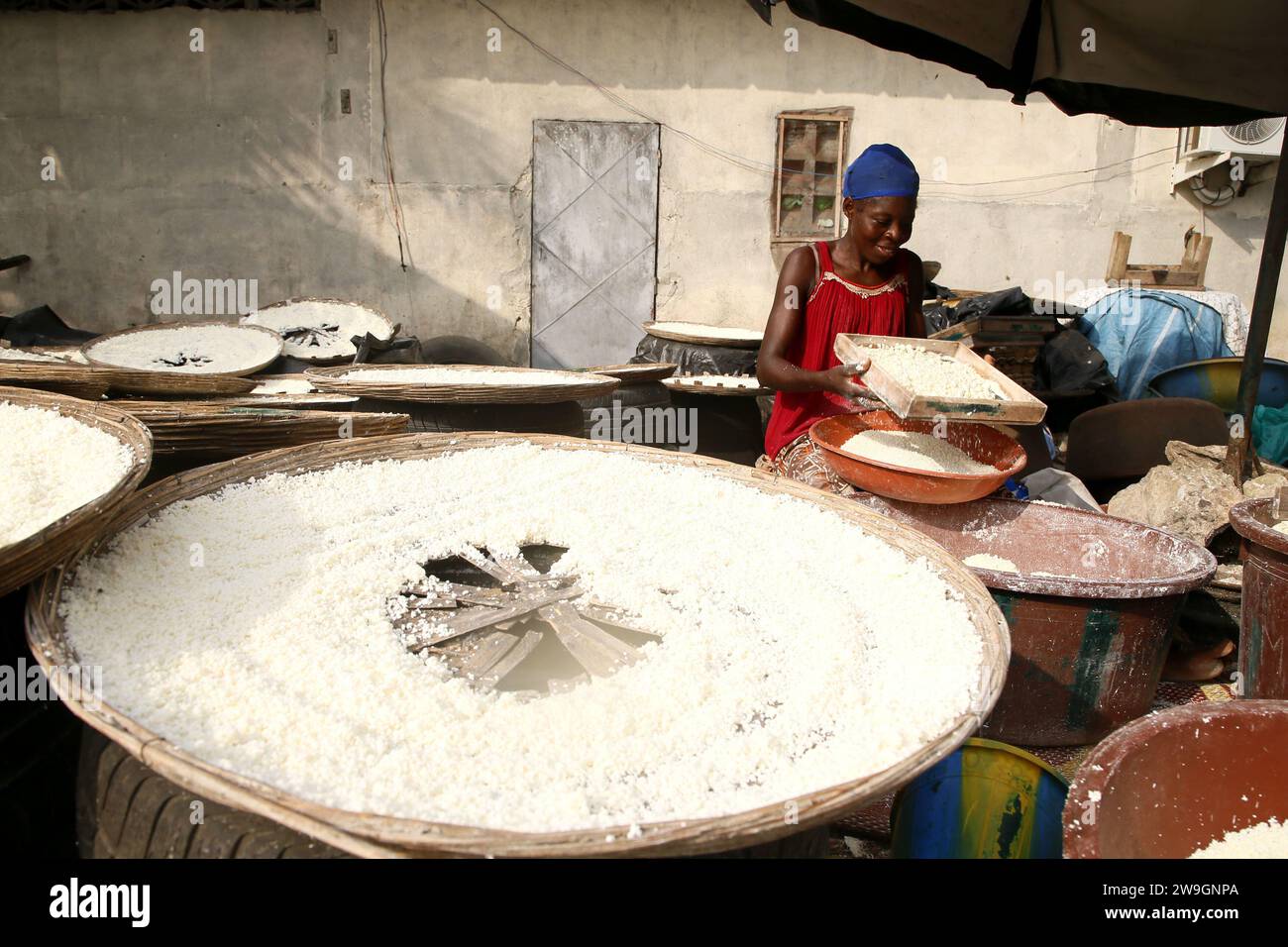 Abidjan, Cote d'Ivoire. 27th Dec, 2023. A woman drys cassava root ...