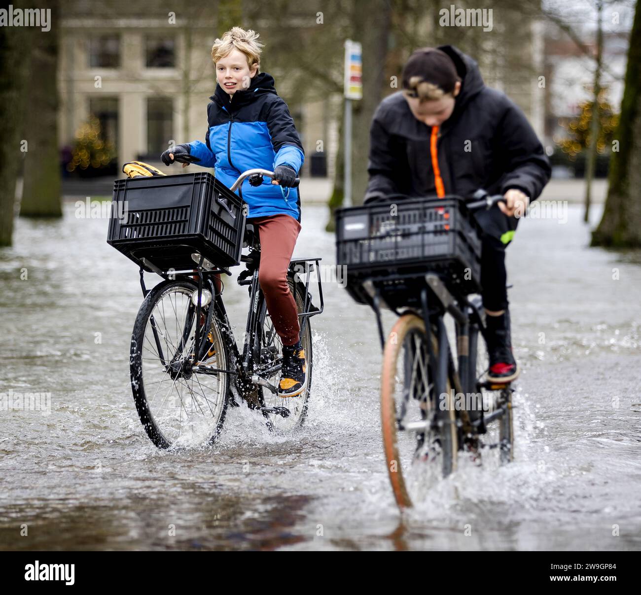 DEVENTER - Young people cycle through a flooded street in Deventer. The ...