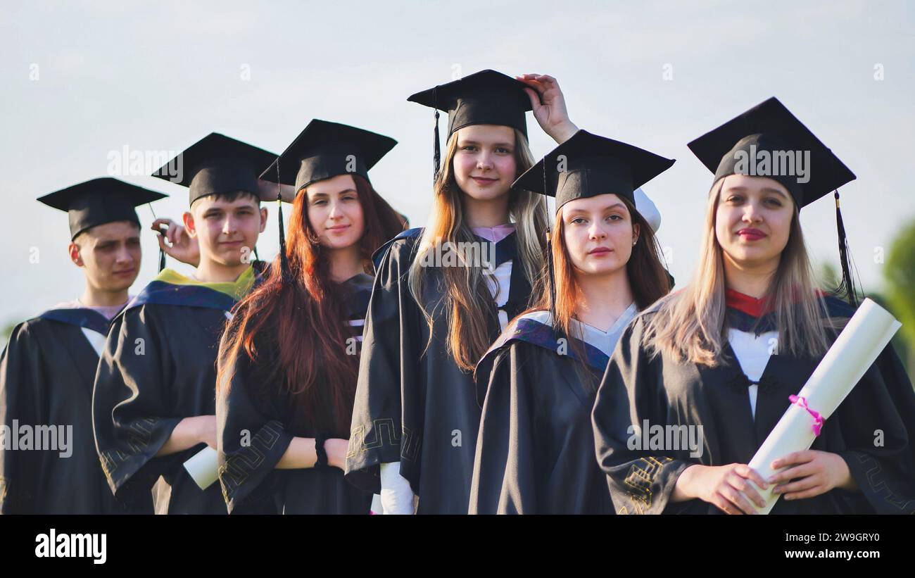 Cheerful graduates pose with raised diplomas on a sunny day Stock Photo ...