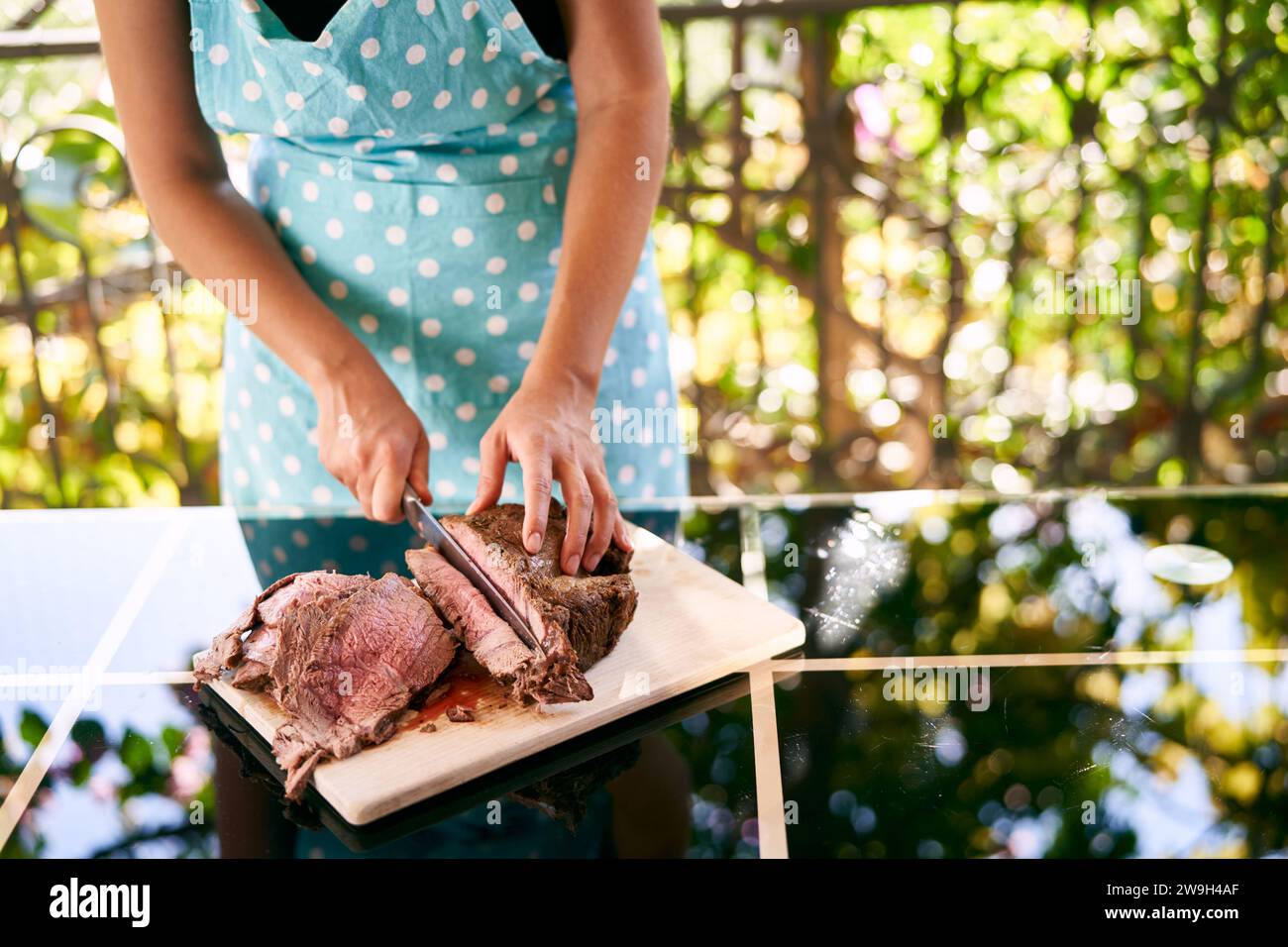 Cook cuts the roast beef with blood on a wooden board on the table on ...