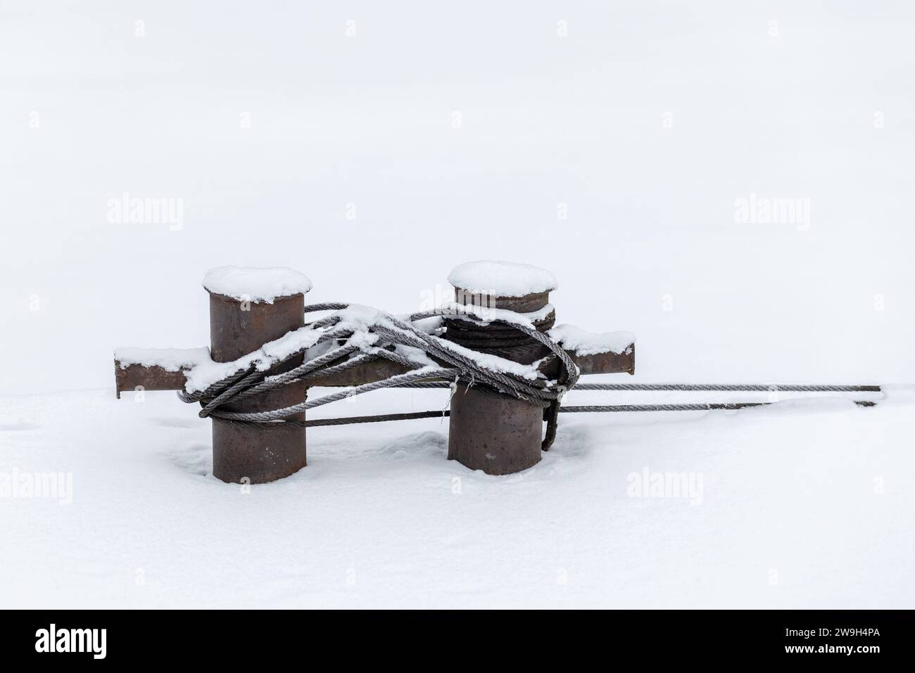 Mooring bollard with steel rope covered with snow, close up photo Stock ...