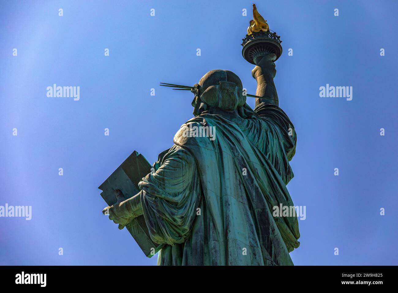 Rear photo of the Statue of Liberty holding her torch on a sunny day in ...