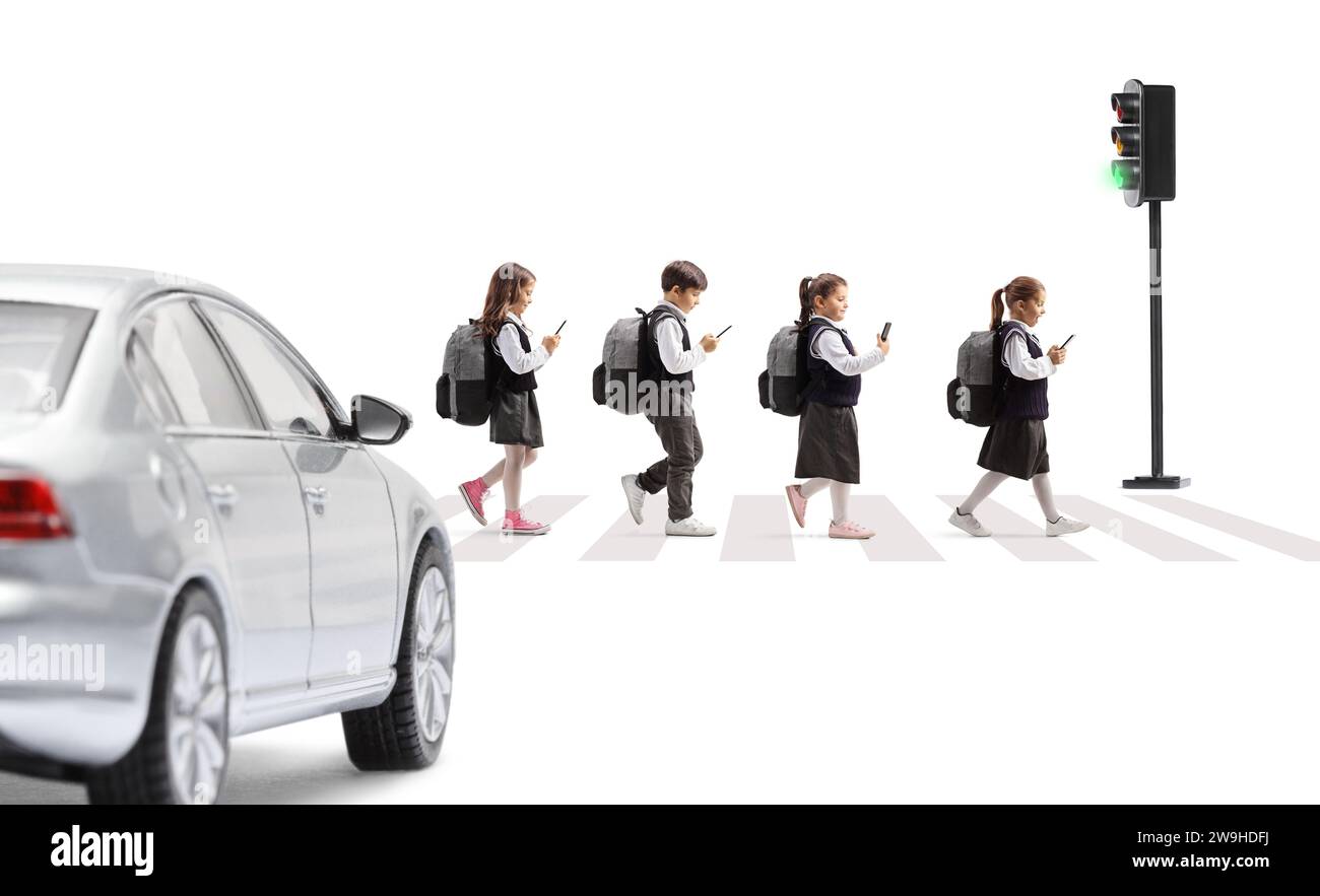 Schoolchildren with mobile phones crossing a street in front of a car ...