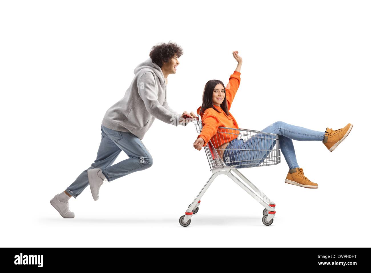 Guy running and pushing a happy young female inside a shopping cart ...