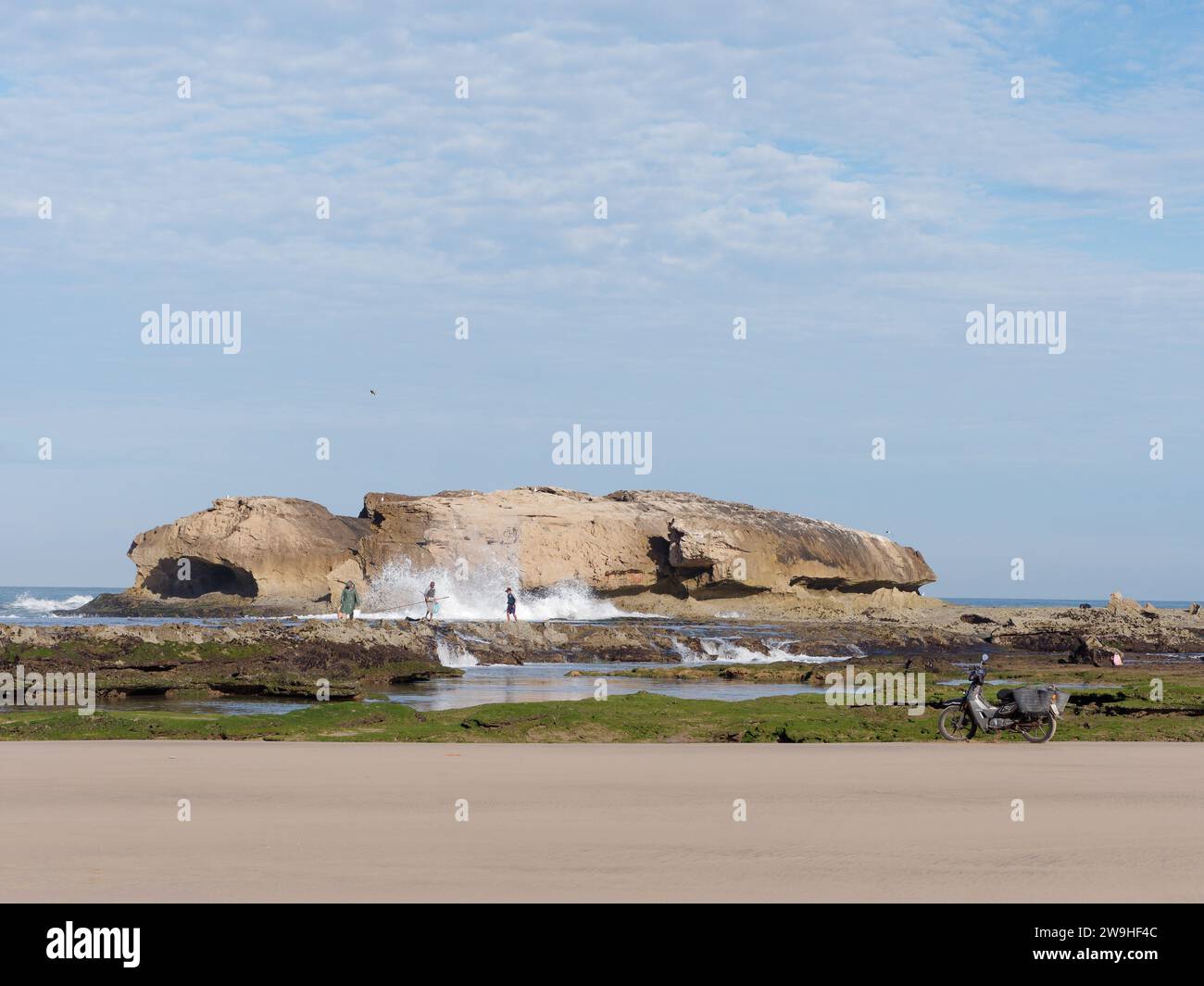 Local fisherman beside large rocky outcrop next to a sandy beach as ...