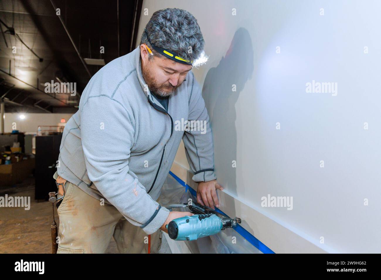 Contractor nails worker using an air gun during installation of wooden ...