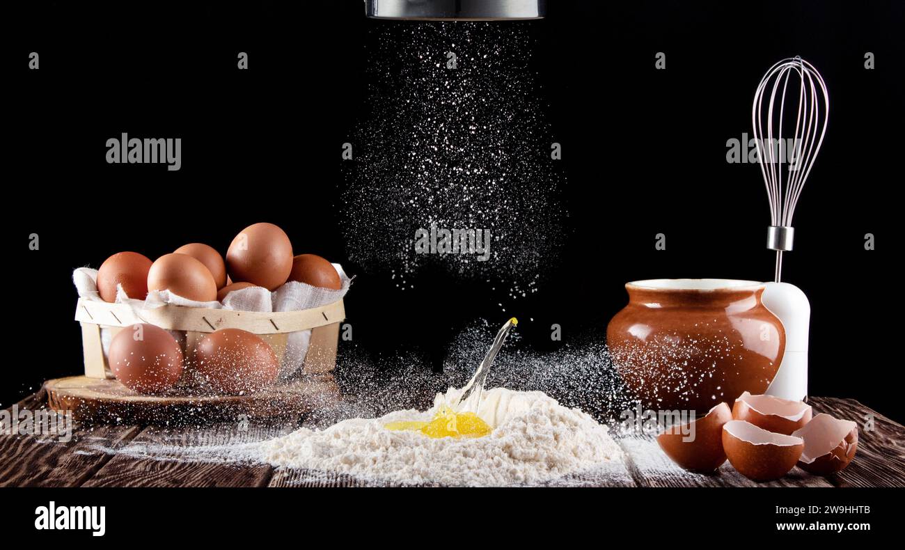 A frozen photograph of falling flour. The flour is poured onto a wooden ...