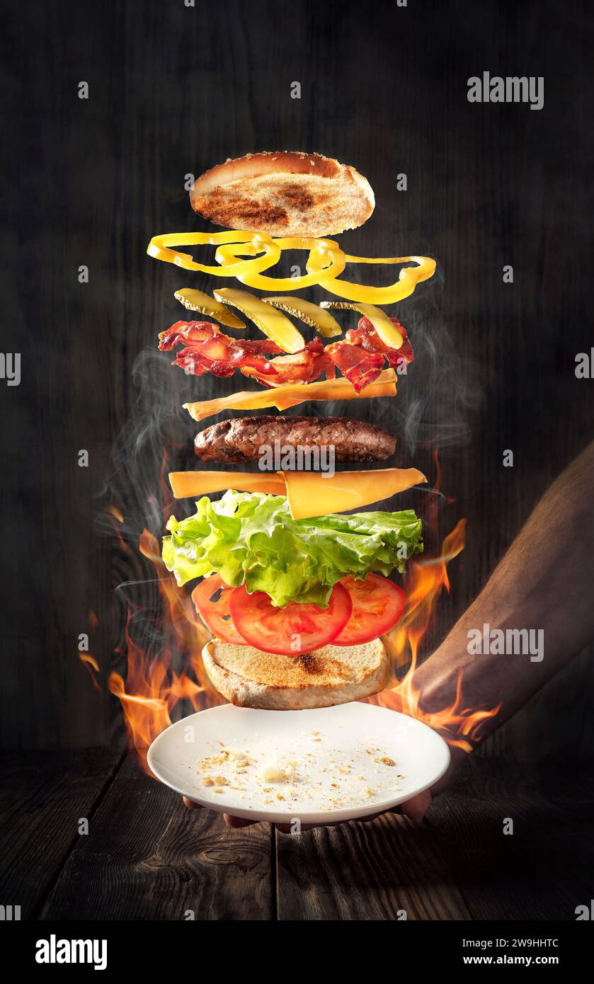 Tasty hamburger with flying ingredients. A hamburger flies over a plate ...
