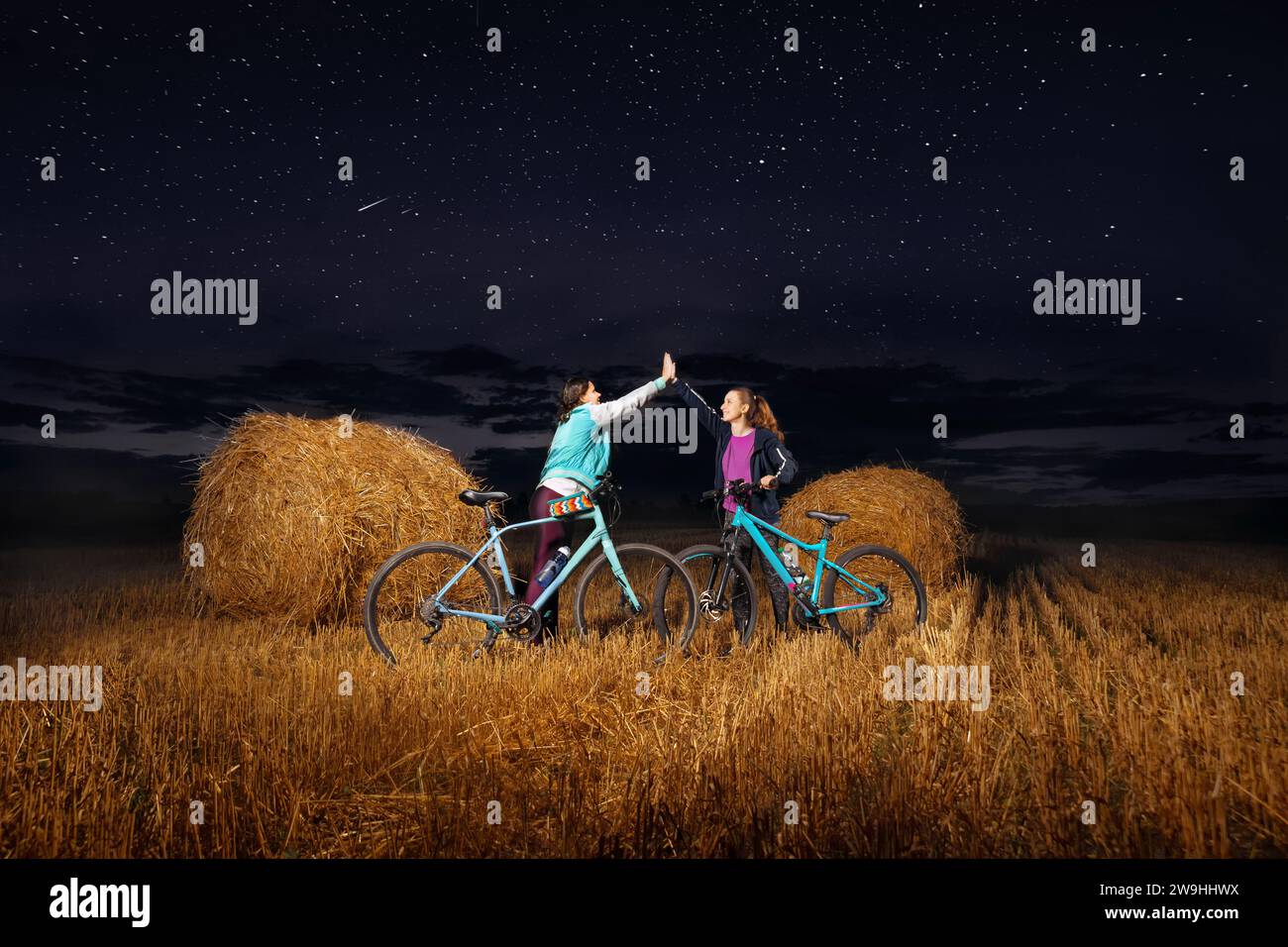 Happy girls with bicycles giving high five to each other. Beautiful ...