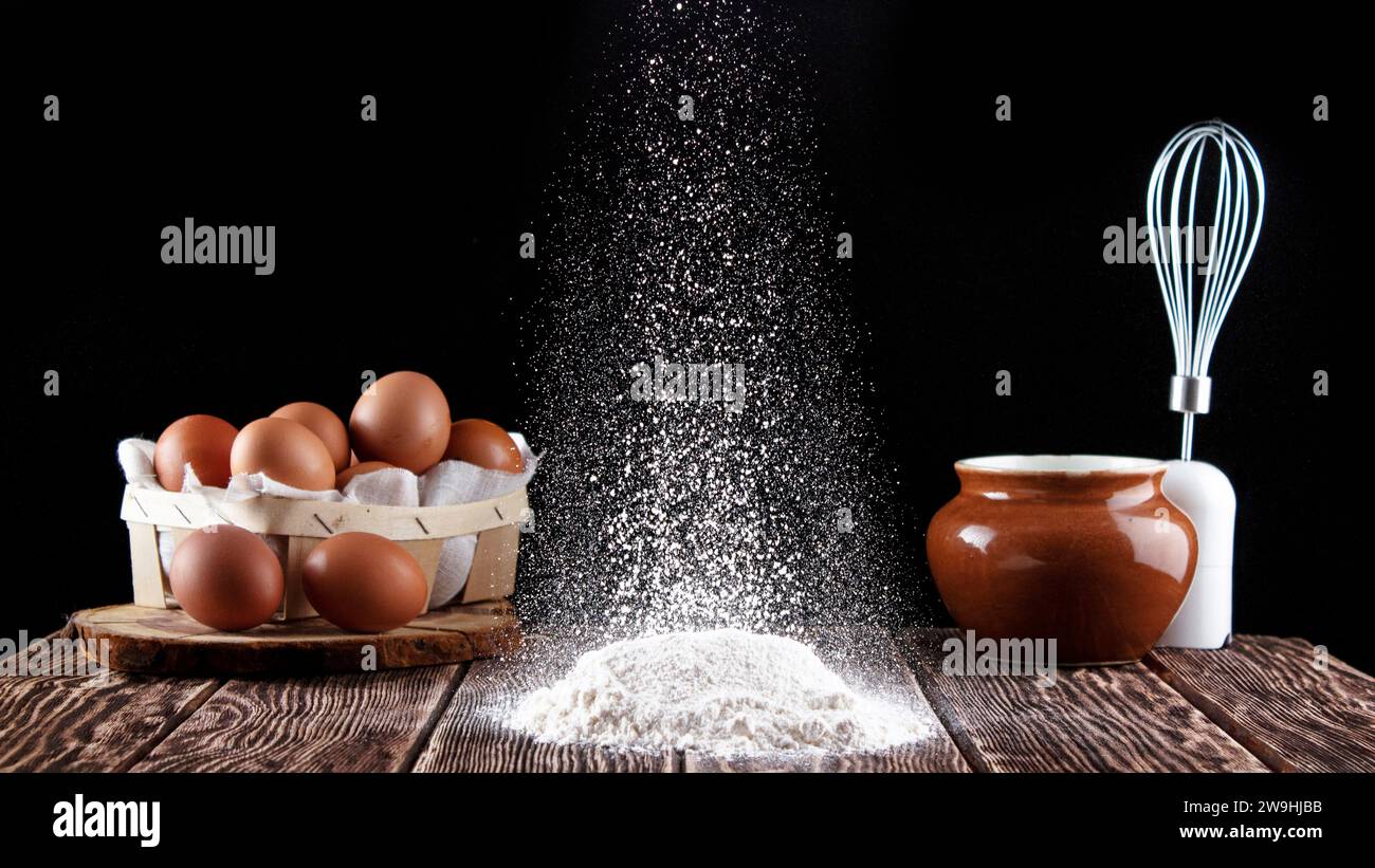Frozen photo of a falling flour. Flour is poured on a wooden board with ...