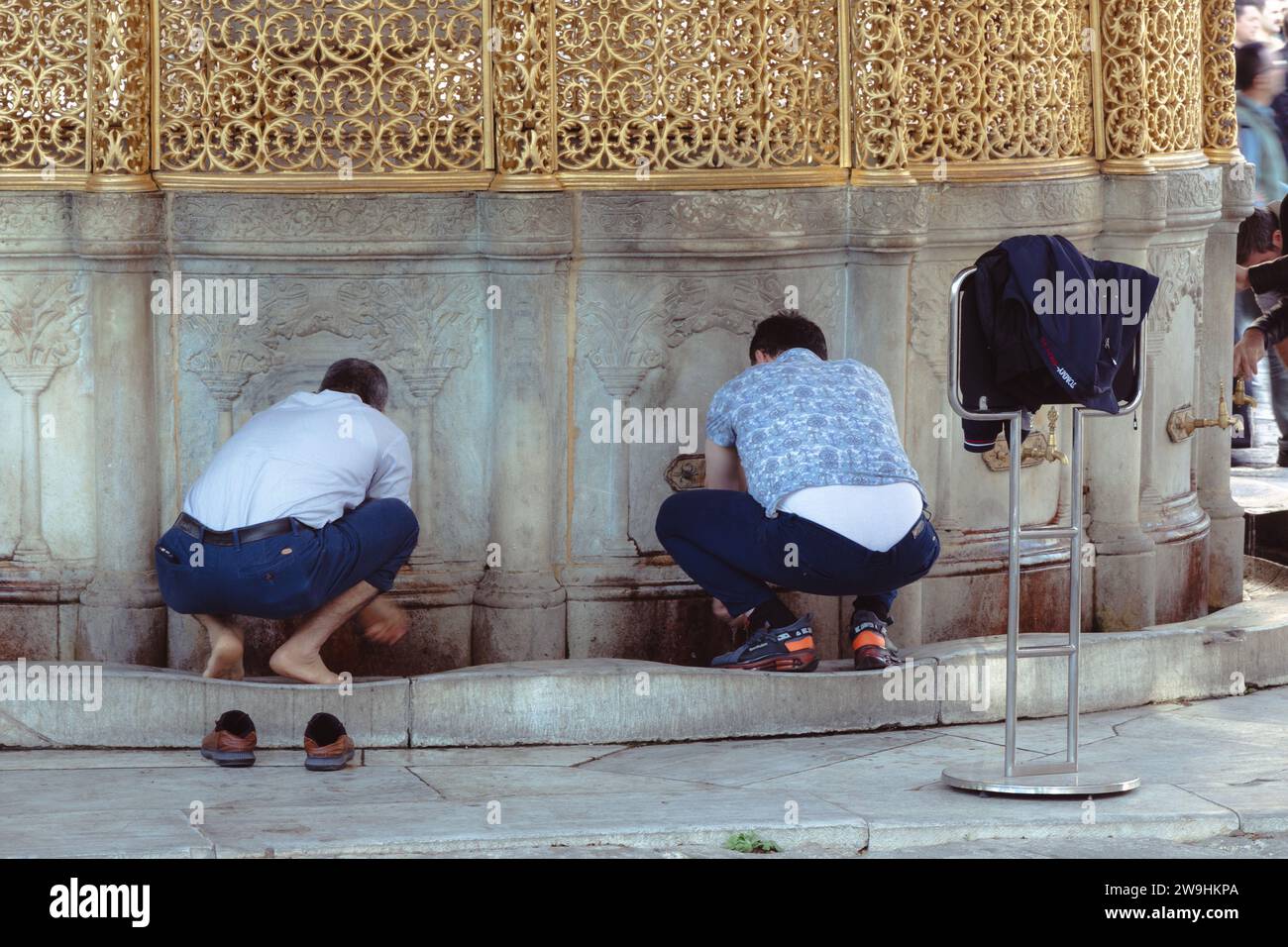 Two muslim man worshippers washing their feet before prayer outside ...