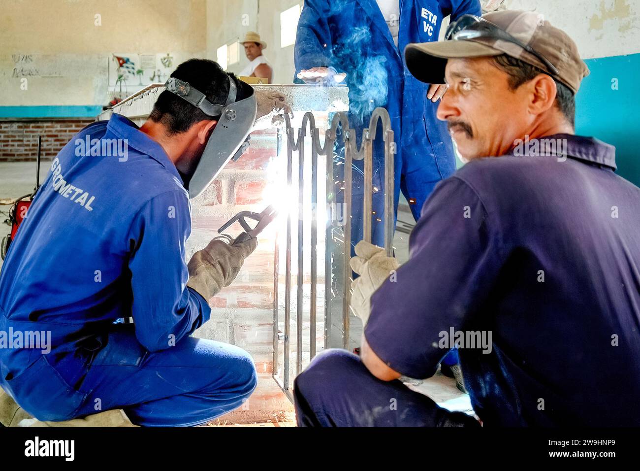 Cuban people working: A welder works on a metal part while another ...