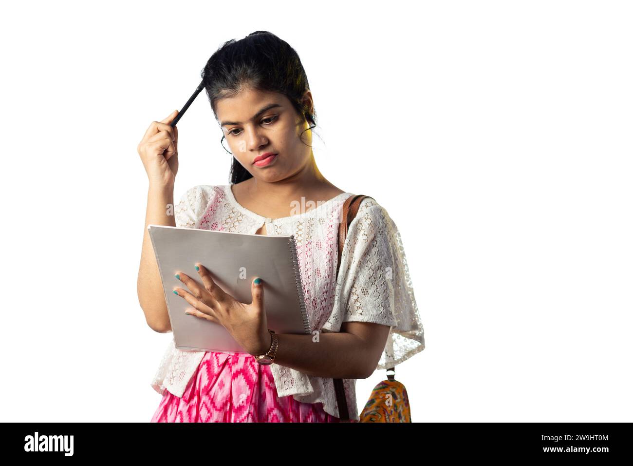 A pretty young Indian girl thinking while taking notes and scratching ...
