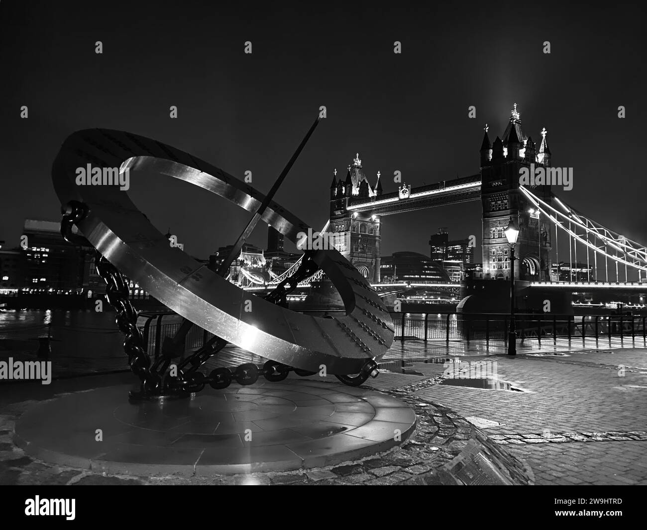 Night shot of sundial on walkway beside the Thames river with Tower ...