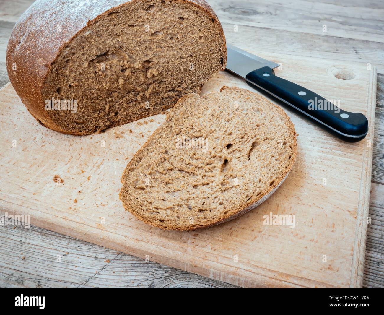 A slice of freshly baked wheat-rye bread with a crispy crust on a beech ...