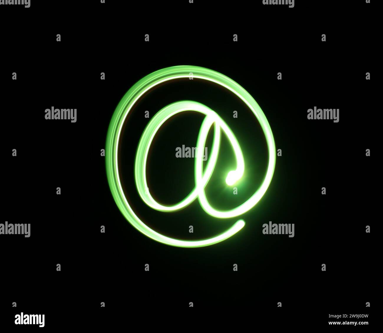 A photograph of an 'at' symbol in vibrant green light in a long ...
