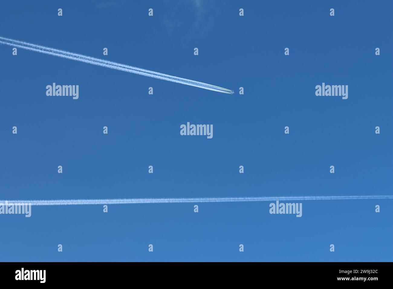 Airplane with contrails in the deep blue sky Stock Photo - Alamy