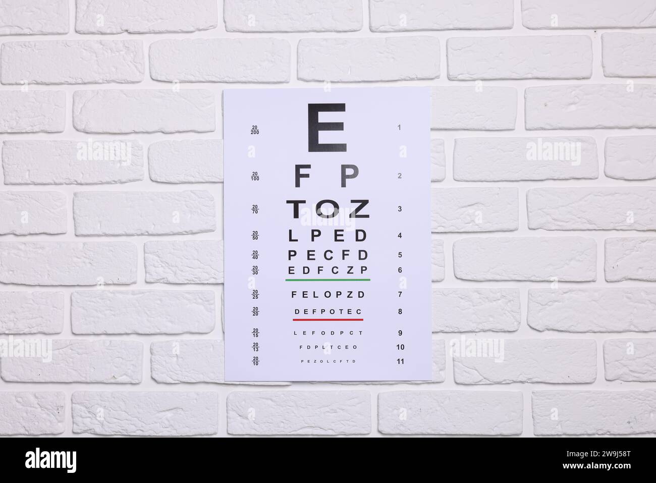 Vision test chart on white brick wall Stock Photo - Alamy