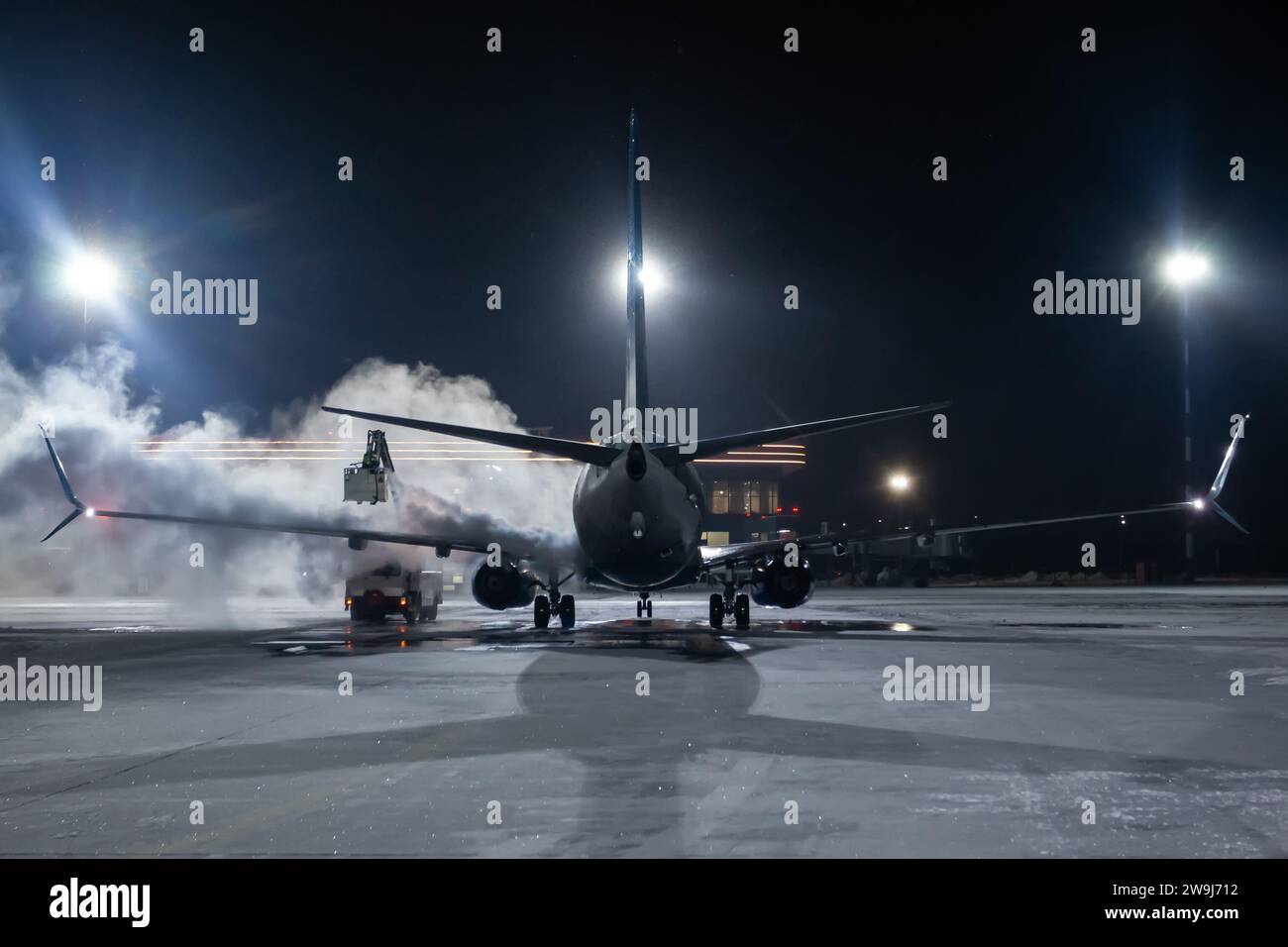 Ground deicing of a passenger jetliner on the night airport apron at ...