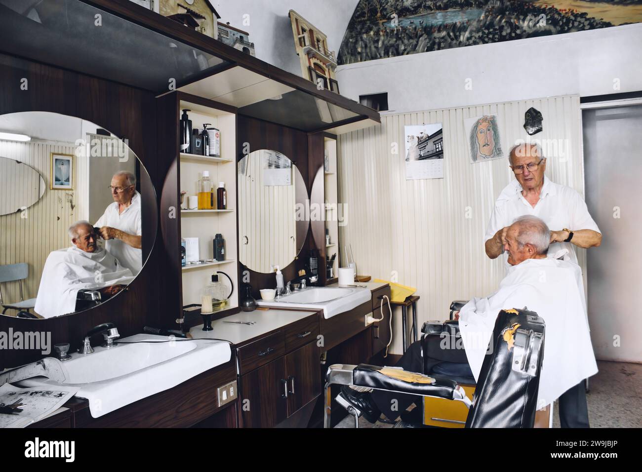 Candid photograph of an old-fashioned barber cutting a man's hair in ...