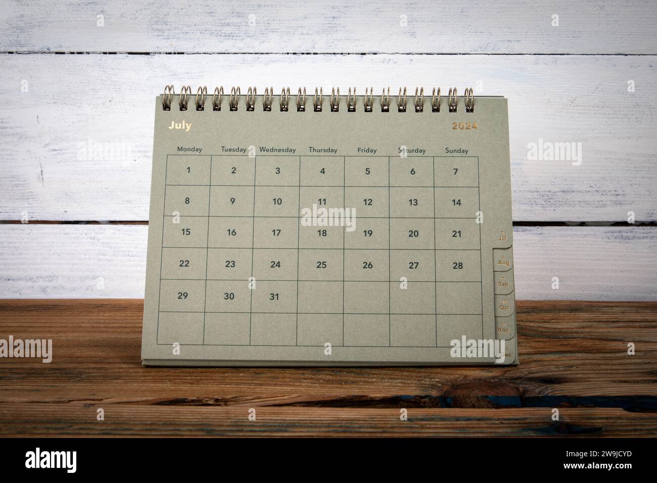 JULY 2024 cardboard desk calendar and planner on a wooden texture table ...