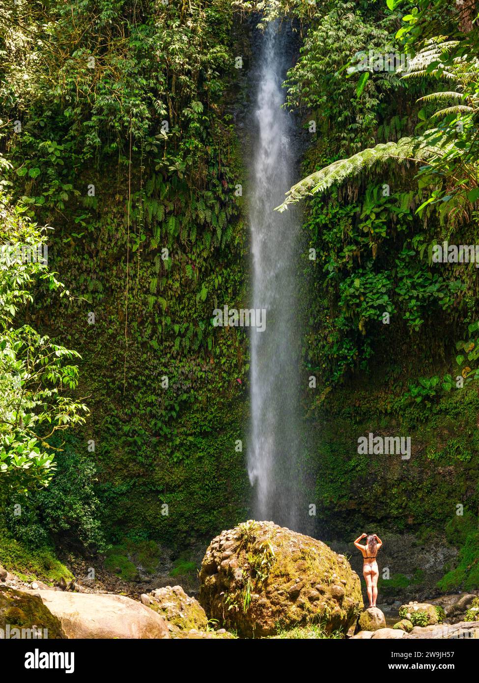 Young woman next to a rock at the Cascada Hola Vida waterfall in the ...