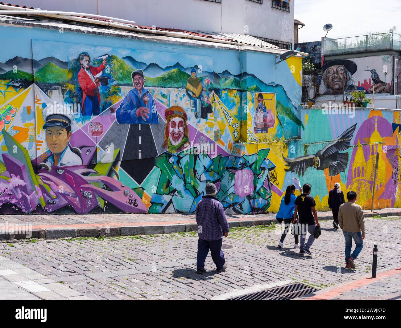 Passers-by walk past artistic street paintings and graffiti, Quito ...