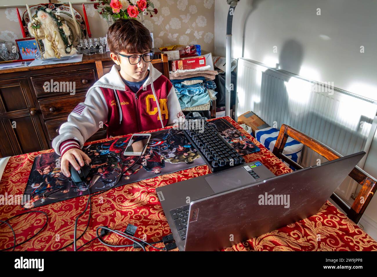 A boy plays a computer game on a laptop computer on a dining room table ...