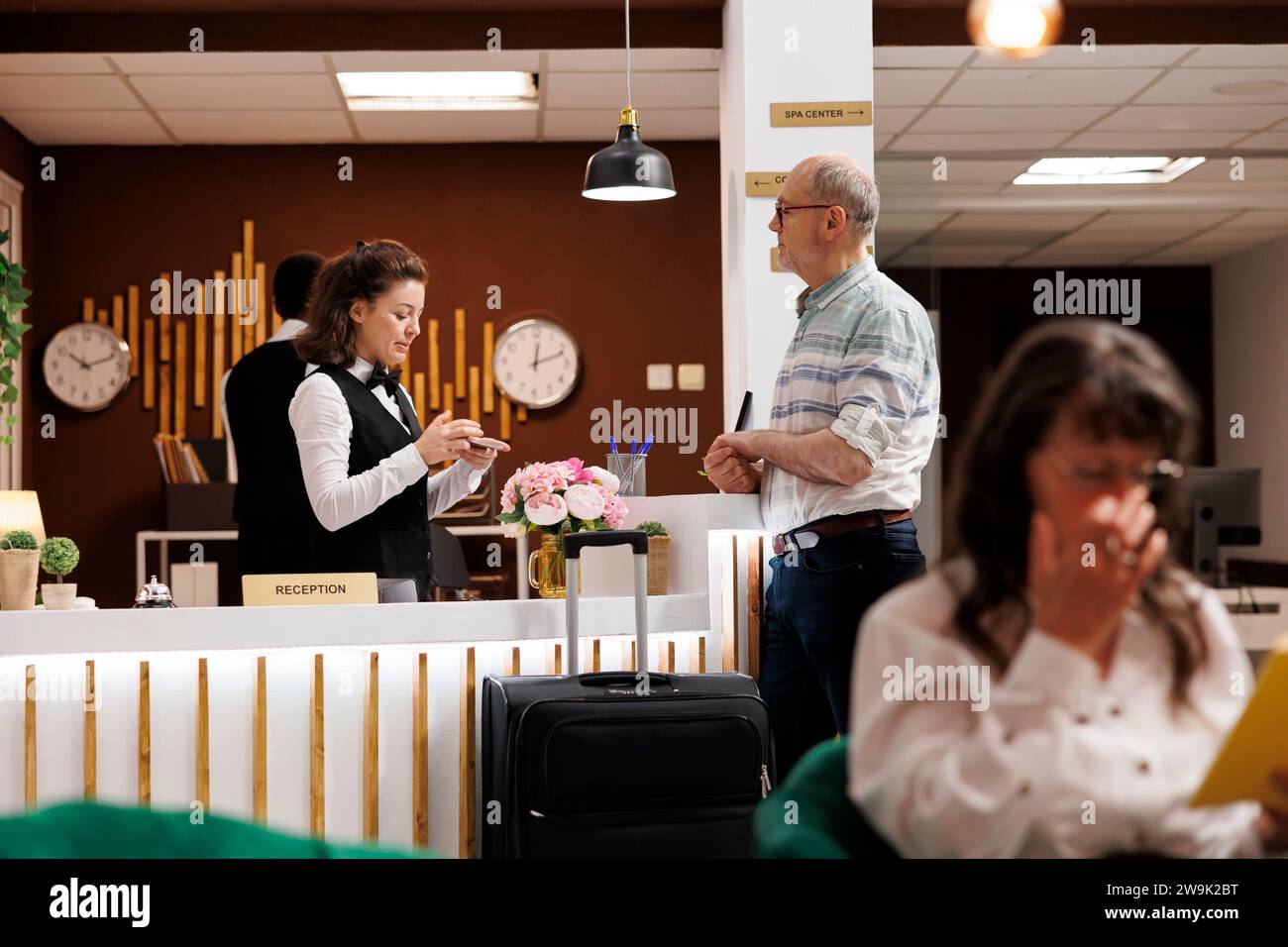 Helpful female concierge assists an elderly male guest with ...