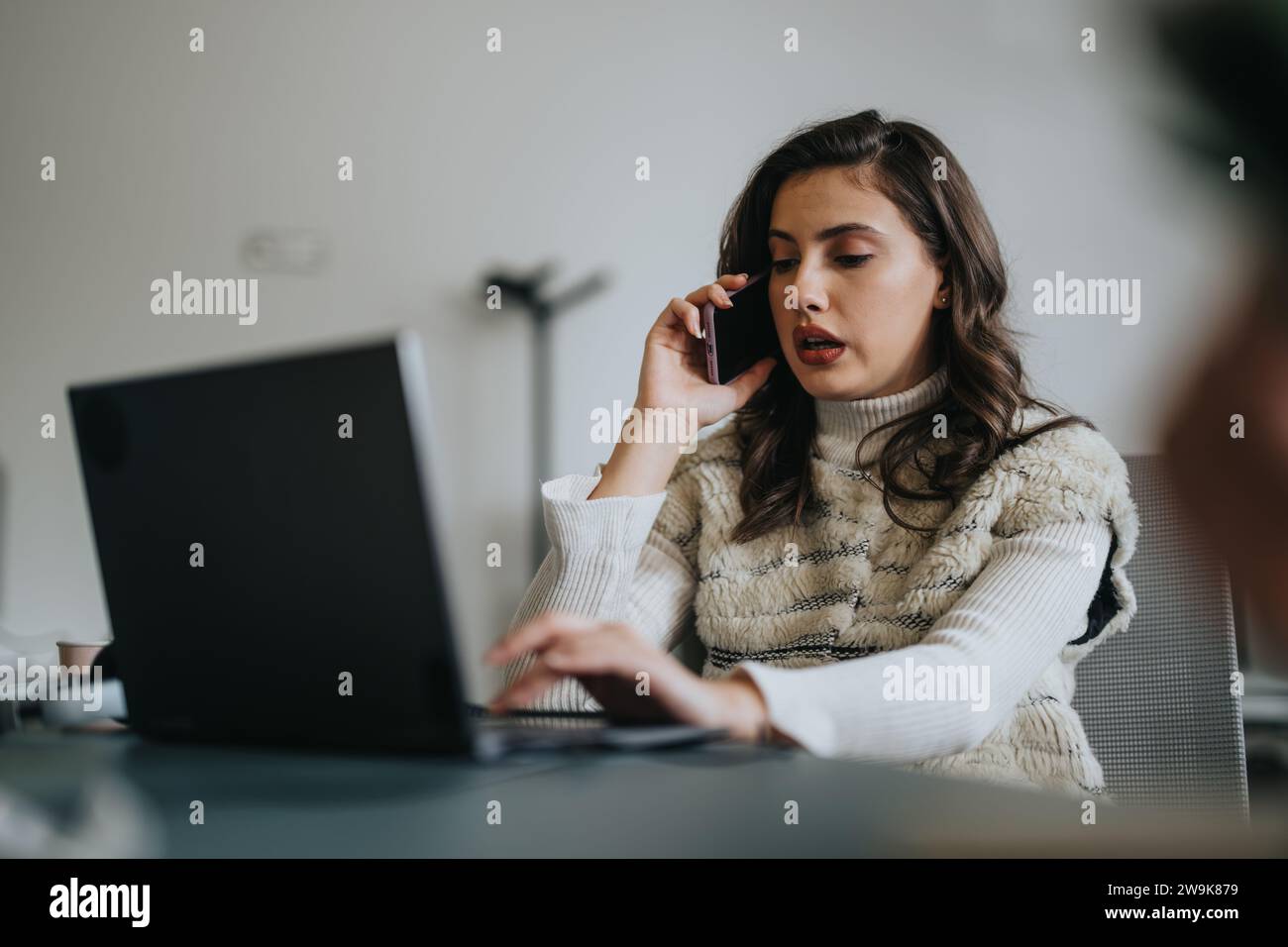Female person having phone call with client while working on lap top at ...