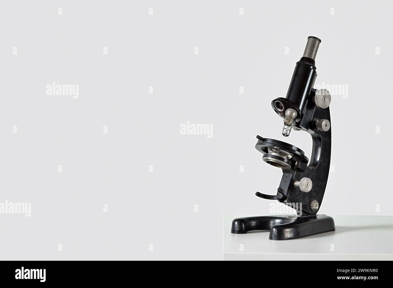 Vintage microscope on table near light wall Stock Photo - Alamy