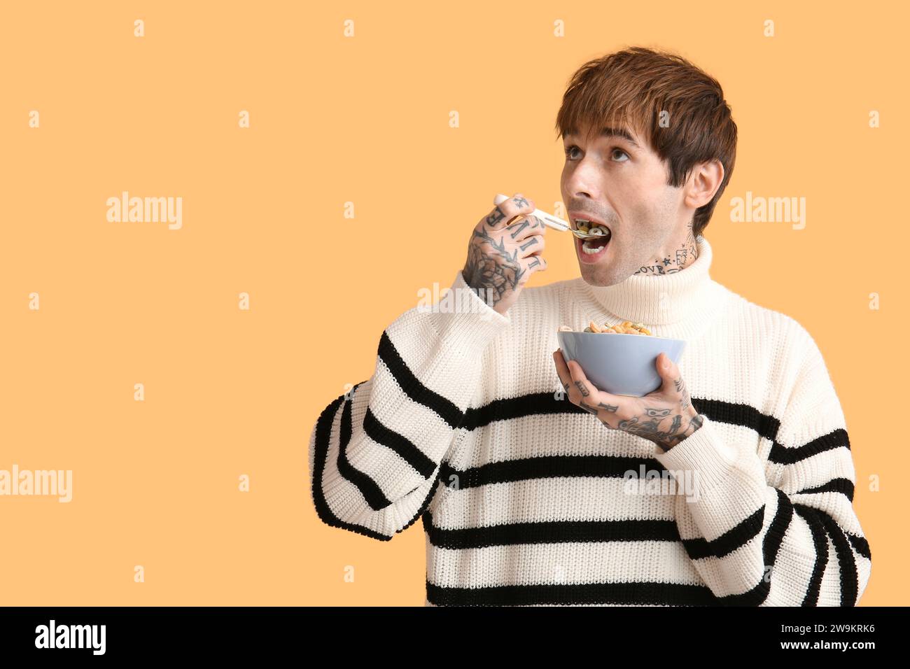 Man eating cereal rings on yellow background Stock Photo - Alamy