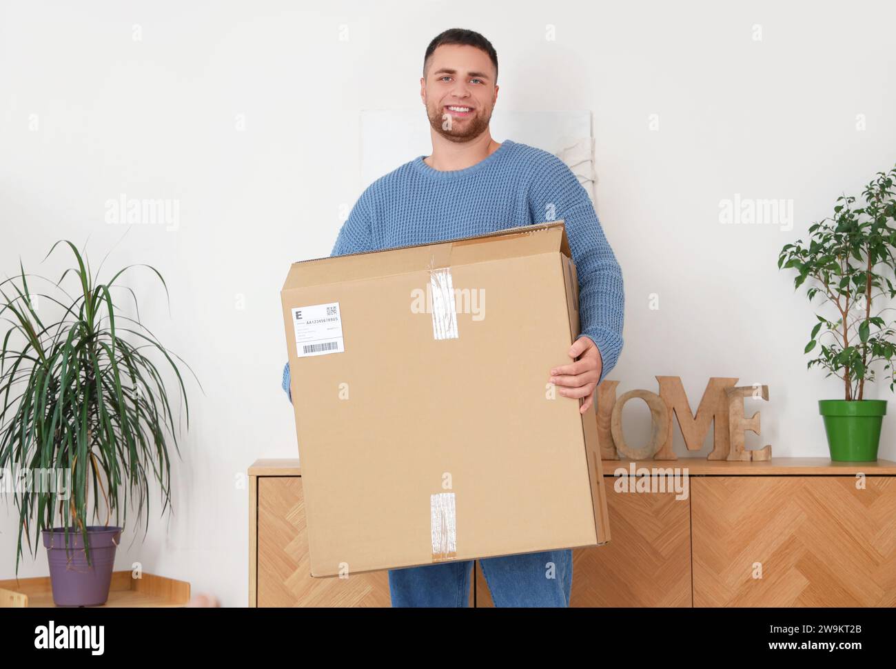 Young man with big parcel box at home Stock Photo - Alamy