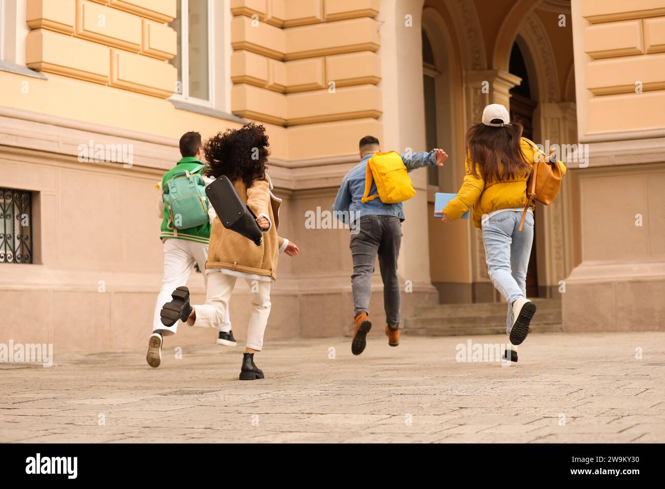 Being late. Group of students running towards building outdoors, back ...