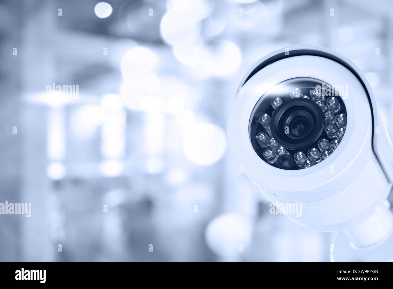 Modern security CCTV camera against blurred background, space for text ...