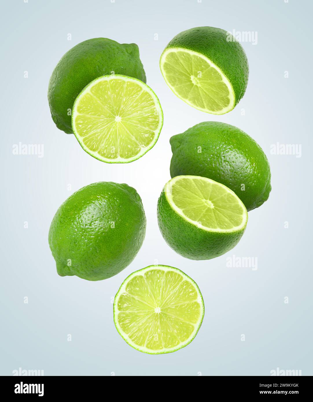 Fresh ripe limes falling on light blue background Stock Photo - Alamy